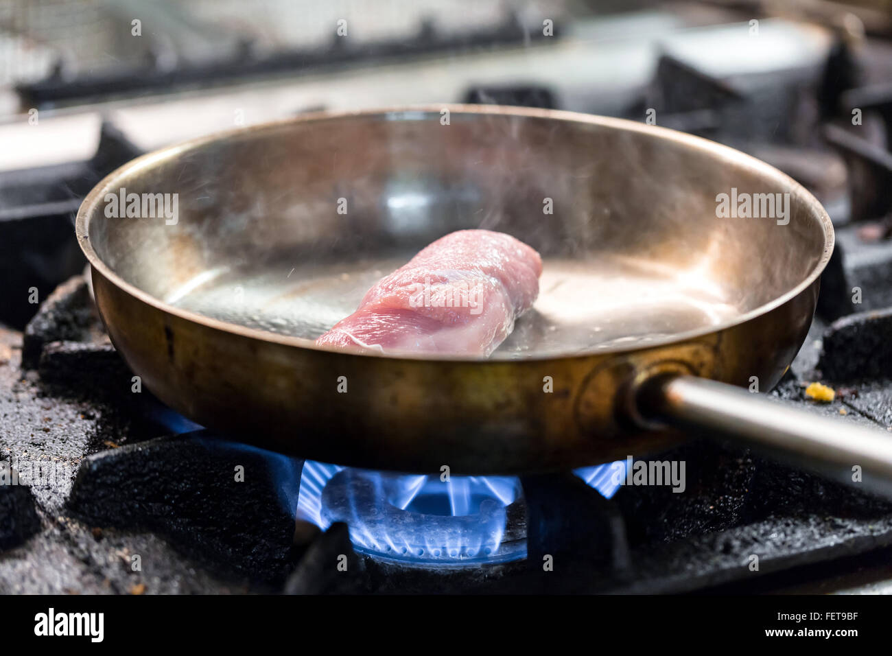 cooking meat in a frying pan Stock Photo - Alamy