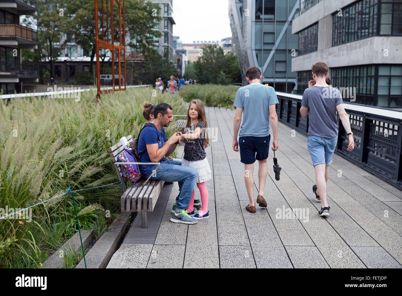 People walk and sit along the path of the High Line park in Manhattan ...
