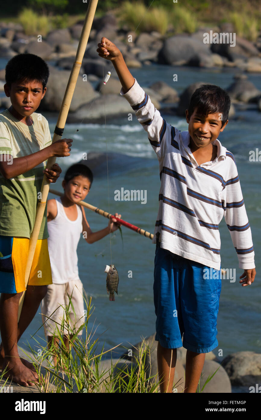 Filipino boys pose for a picture having caught a small fish in a ...