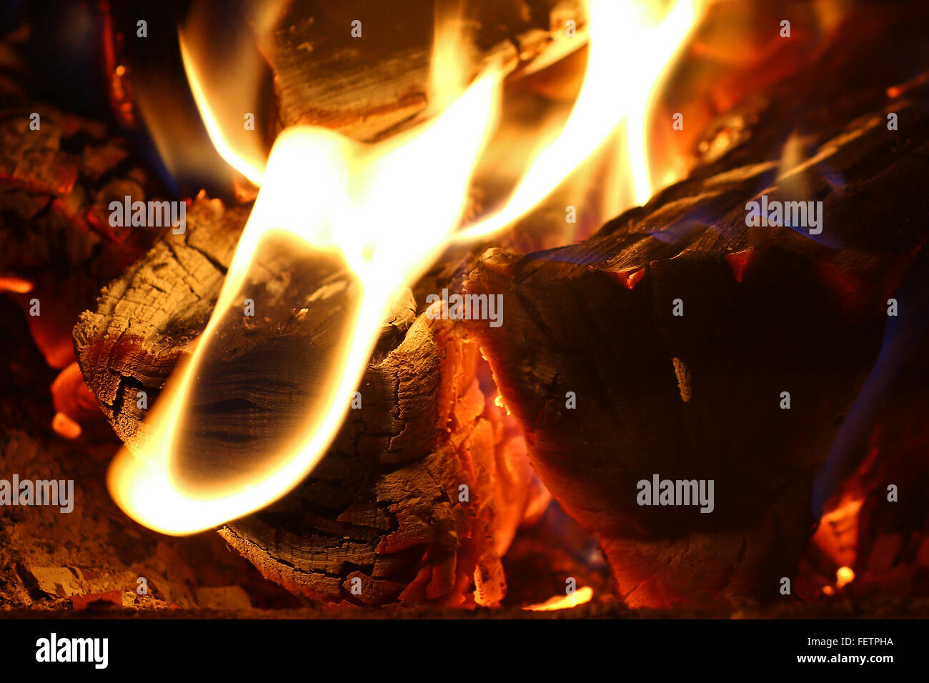 Yellow and orange flames from a burning log campfire Stock Photo - Alamy