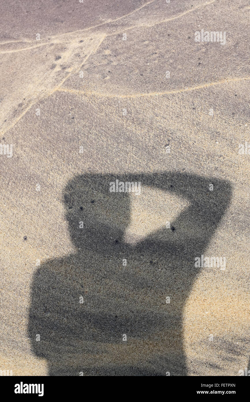 Photographer shadow on grey, purple beach patterns on a tropical beach ...