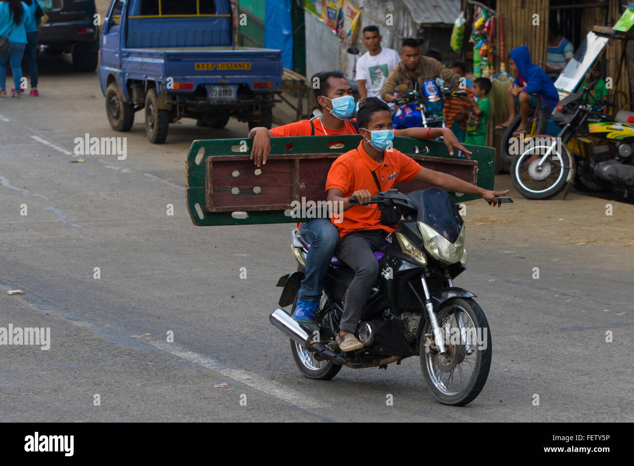 Filipino Medics transport a stretcher board on motorcycle.Rider holding ...