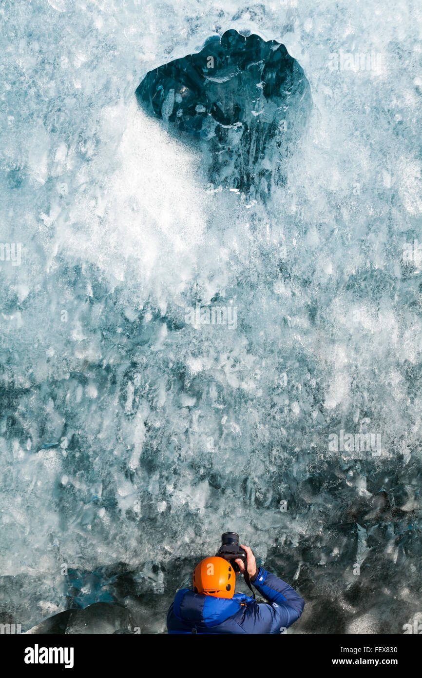 Photographer taking photograph of ice hole in ice cave at ...