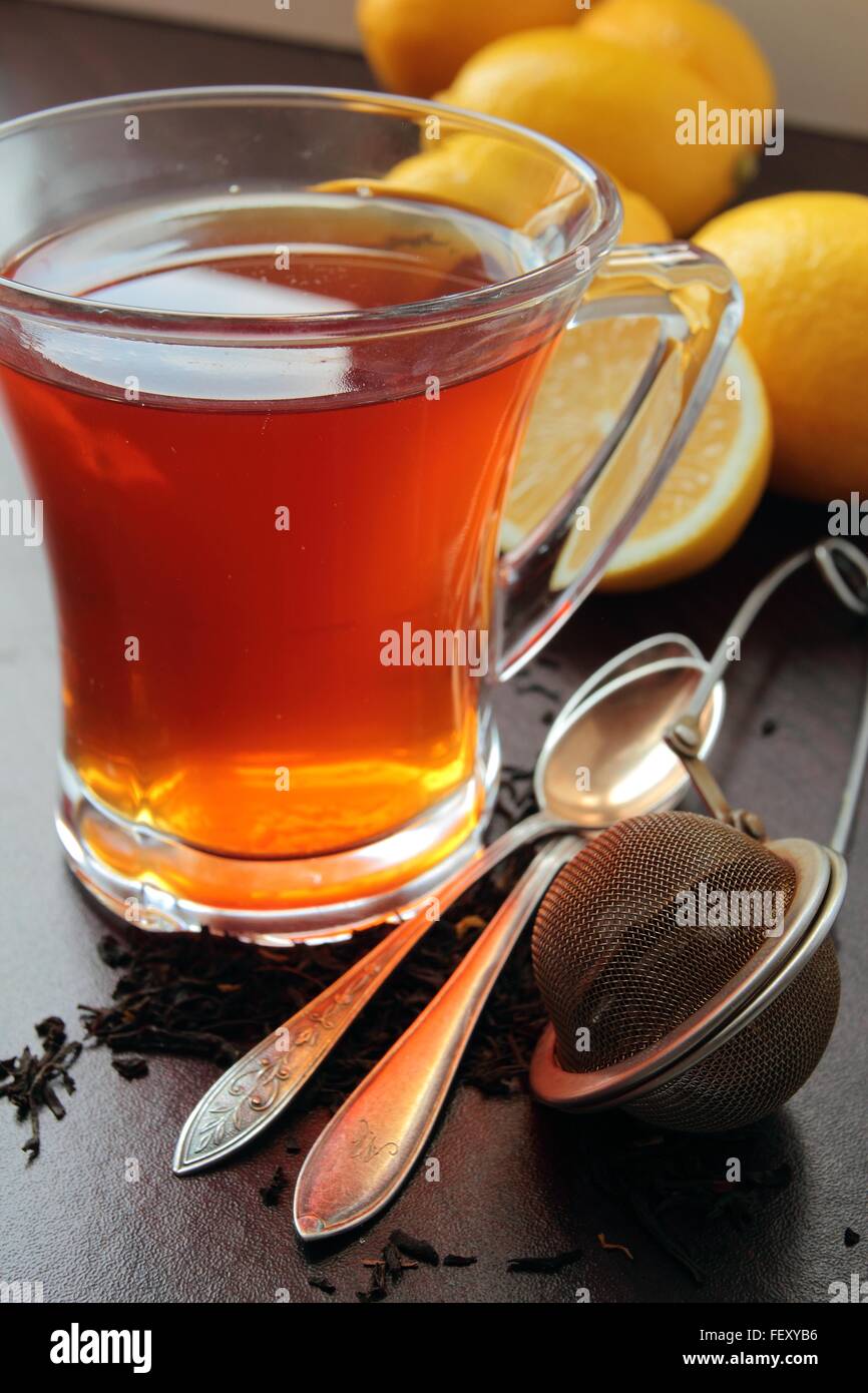 Cup of tea with lemon. Spoons and strainer on table Stock Photo - Alamy