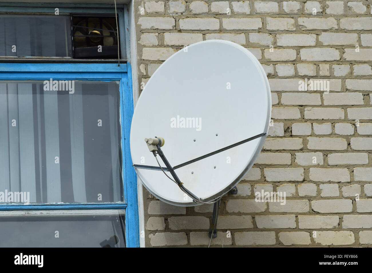 Satellite antenna on the wall near the window. Satellite television ...