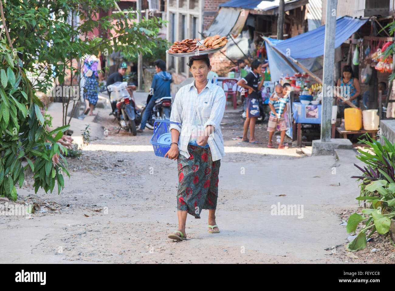 Woman carrying a plate of food at a residential area in Myeik ...