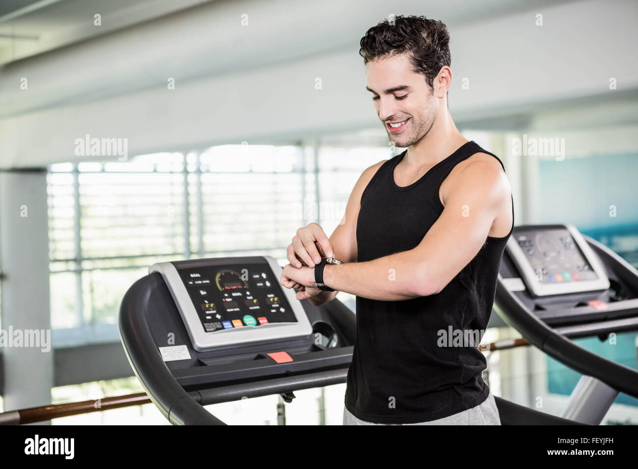 Smiling man on treadmill using smart watch Stock Photo - Alamy
