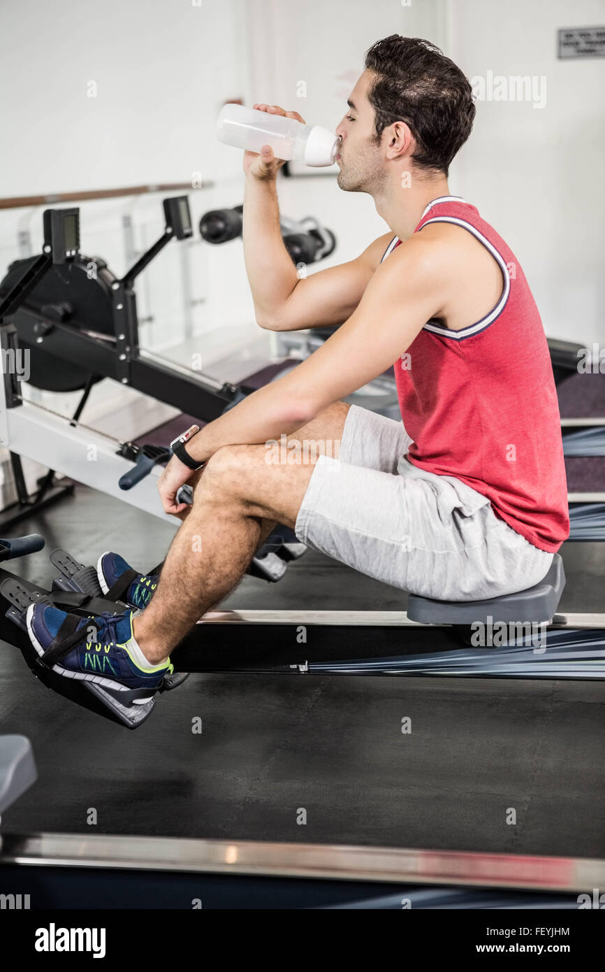 Muscular man on rowing machine drinking water Stock Photo - Alamy