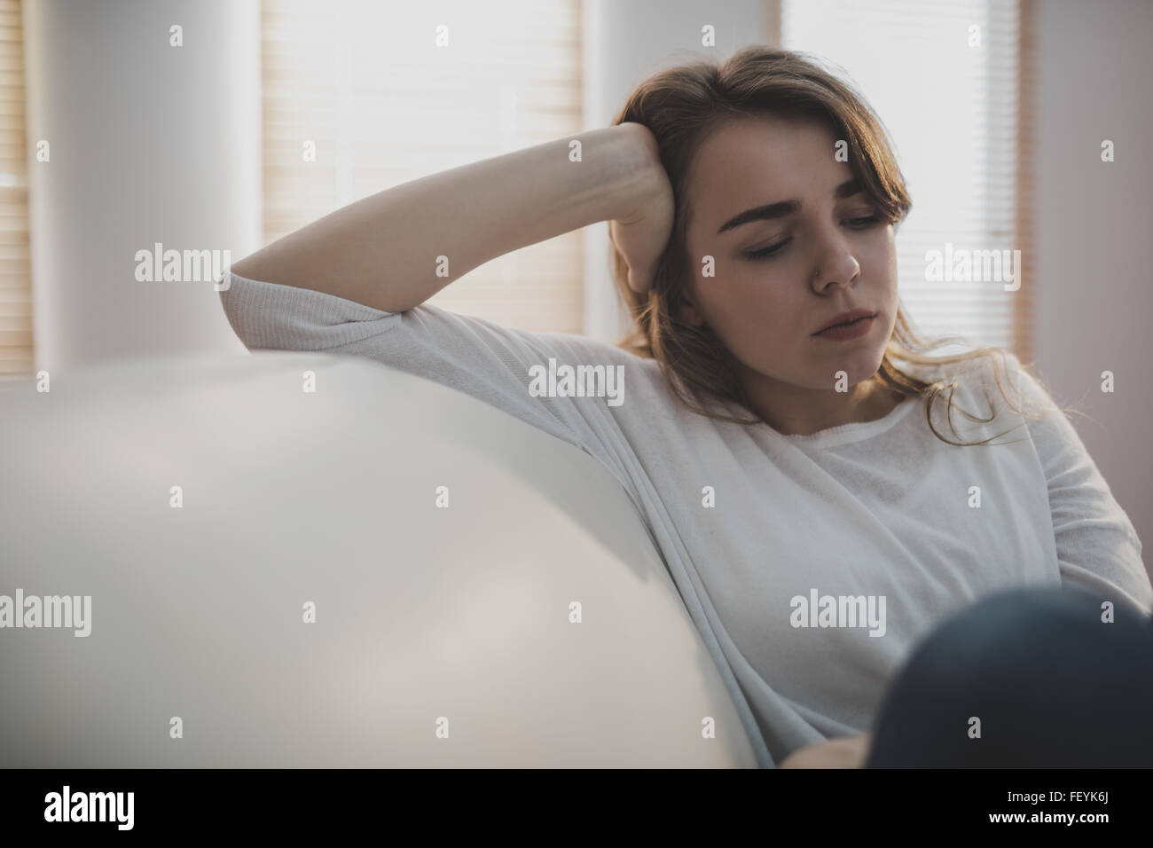 Upset woman sitting on the couch Stock Photo - Alamy