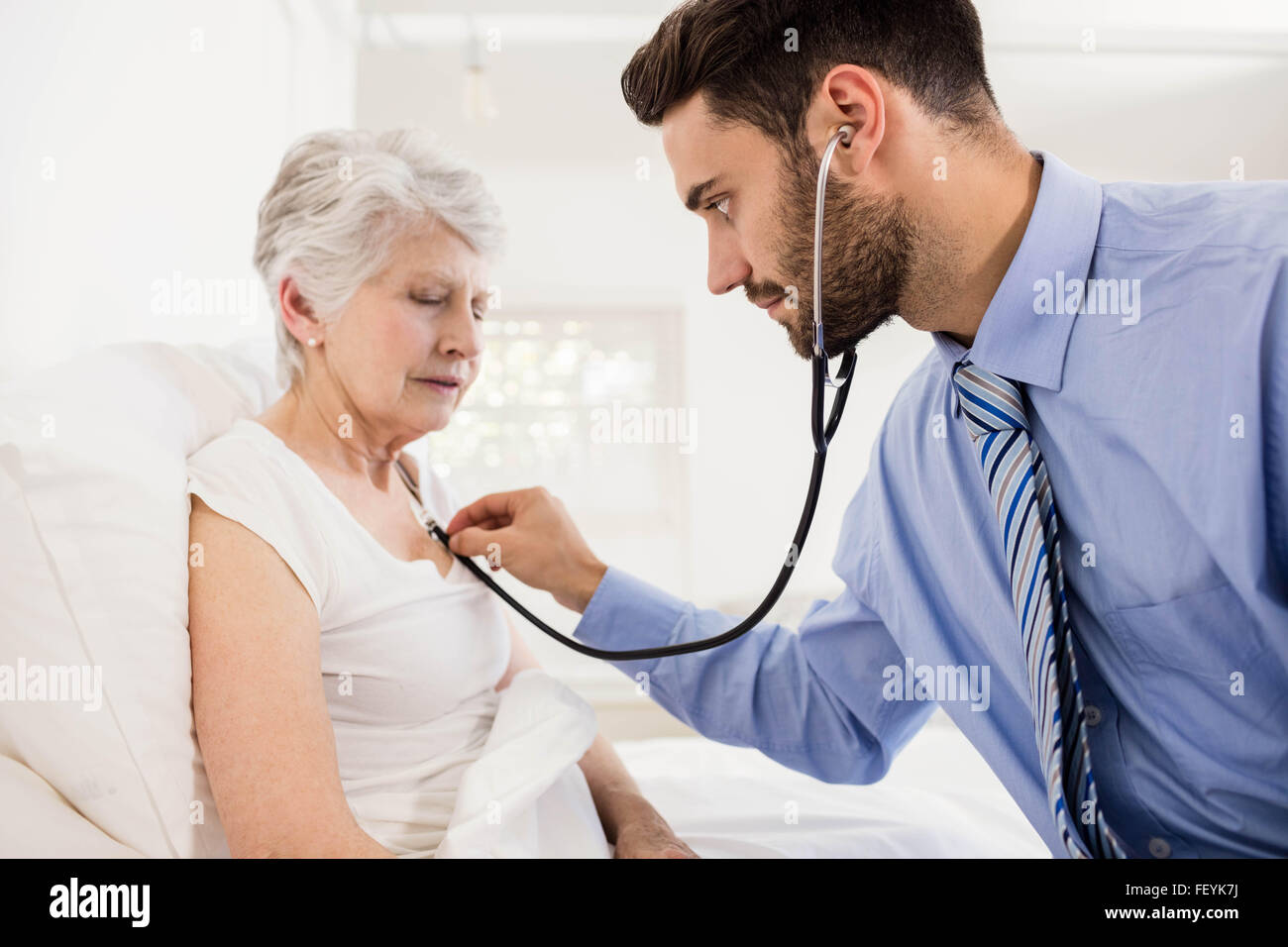 Home nurse listening to chest of patient with stethoscope Stock Photo ...