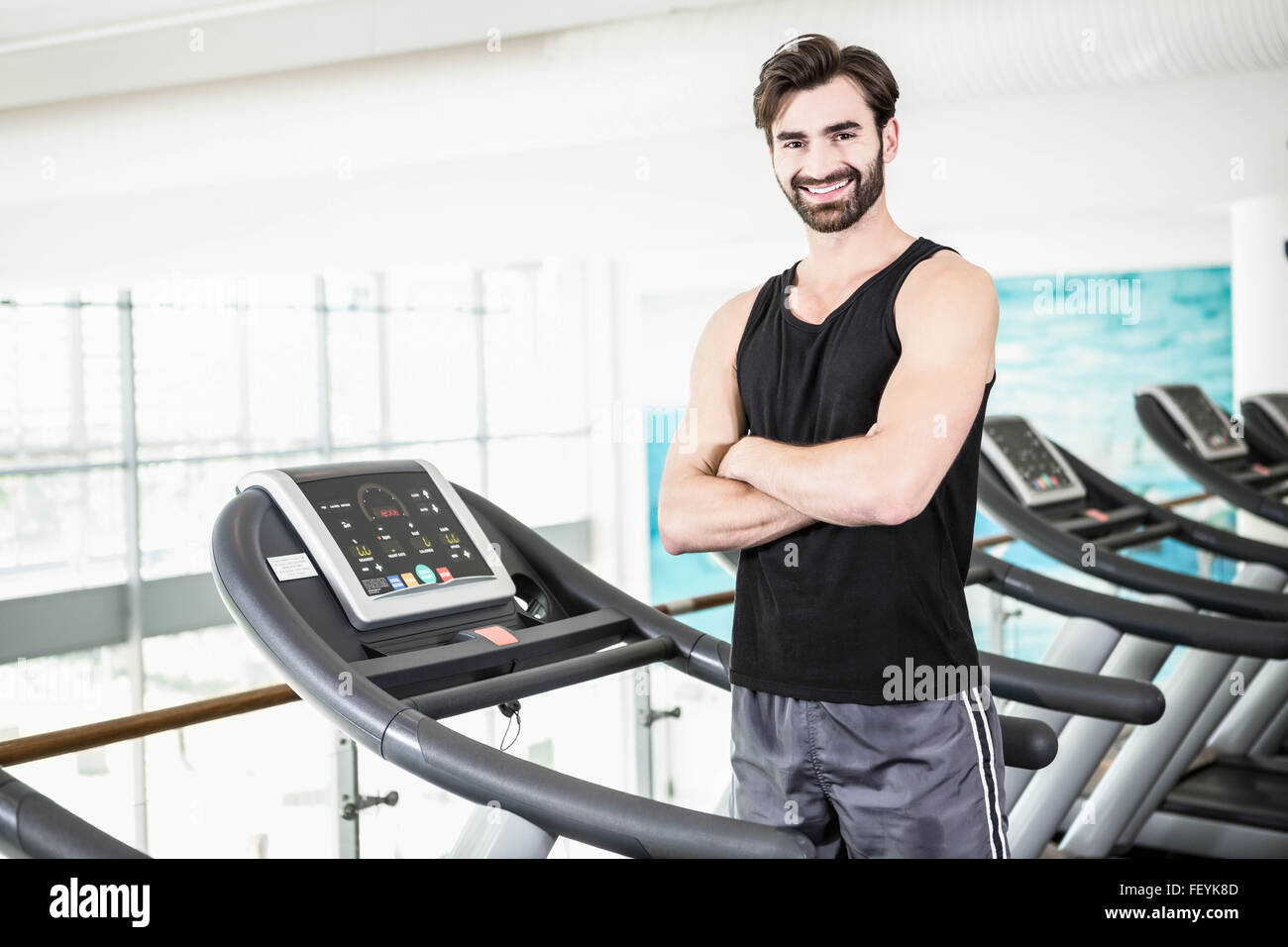 Smiling man standing on treadmill with arms crossed Stock Photo - Alamy