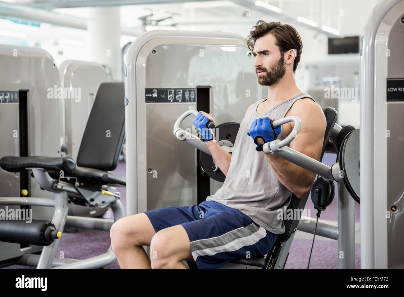 Focused man using weights machine for arms Stock Photo - Alamy
