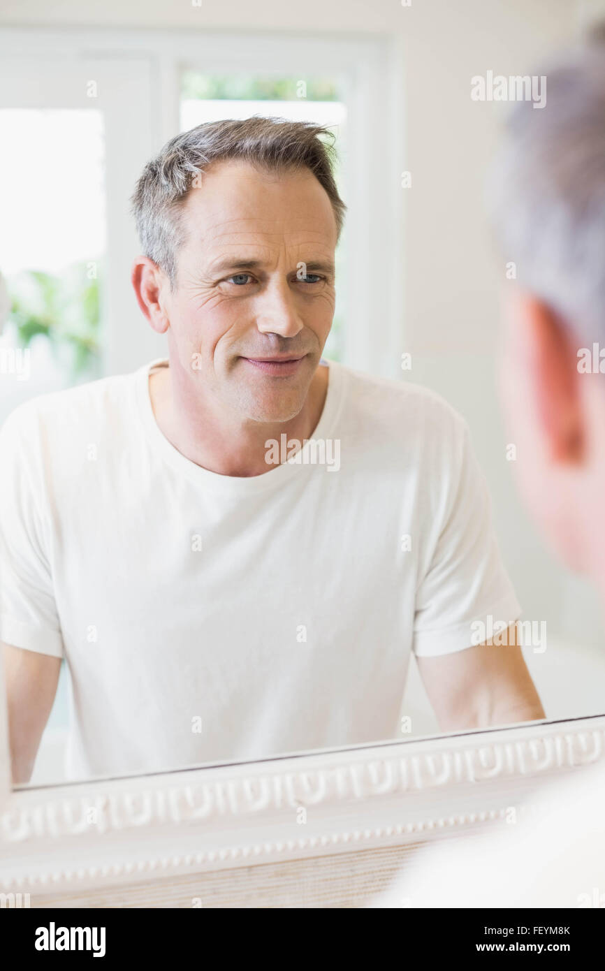 Handsome man looking at himself in the mirror Stock Photo - Alamy