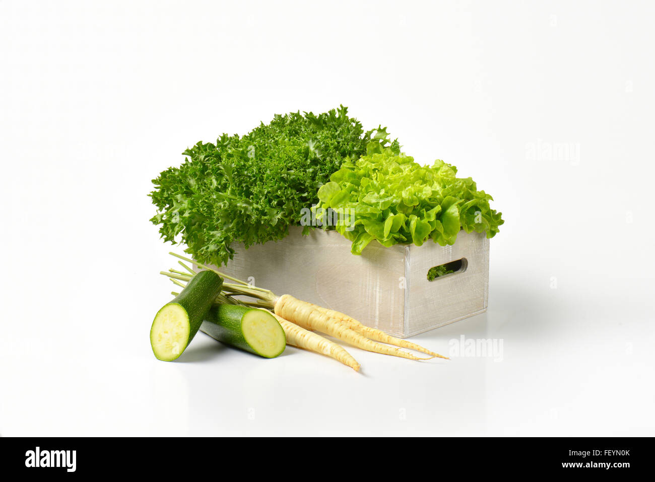box of lettuce, courgette and parsley next to it on white background ...