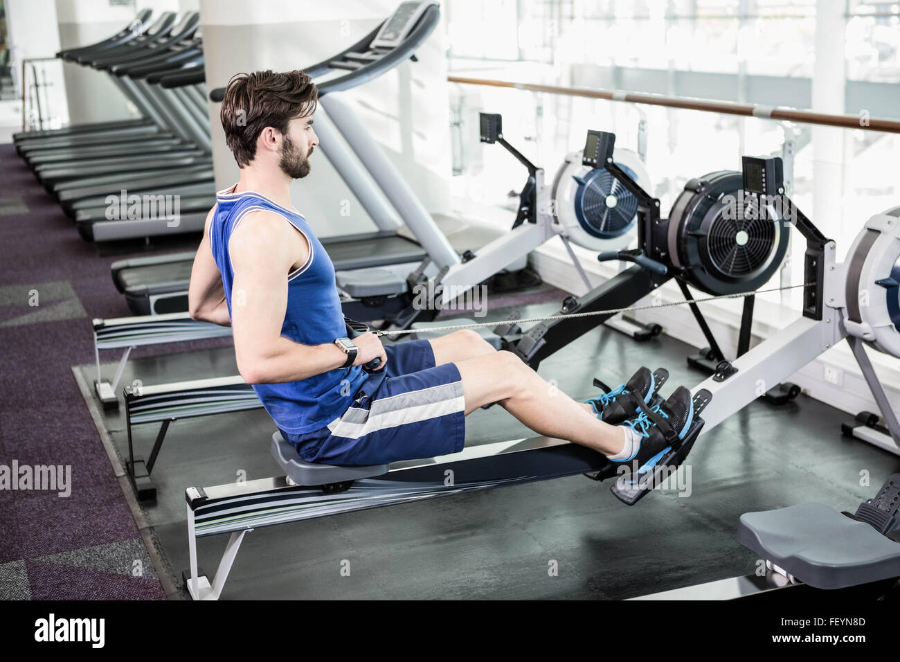 Handsome man doing exercise on drawing machine Stock Photo - Alamy