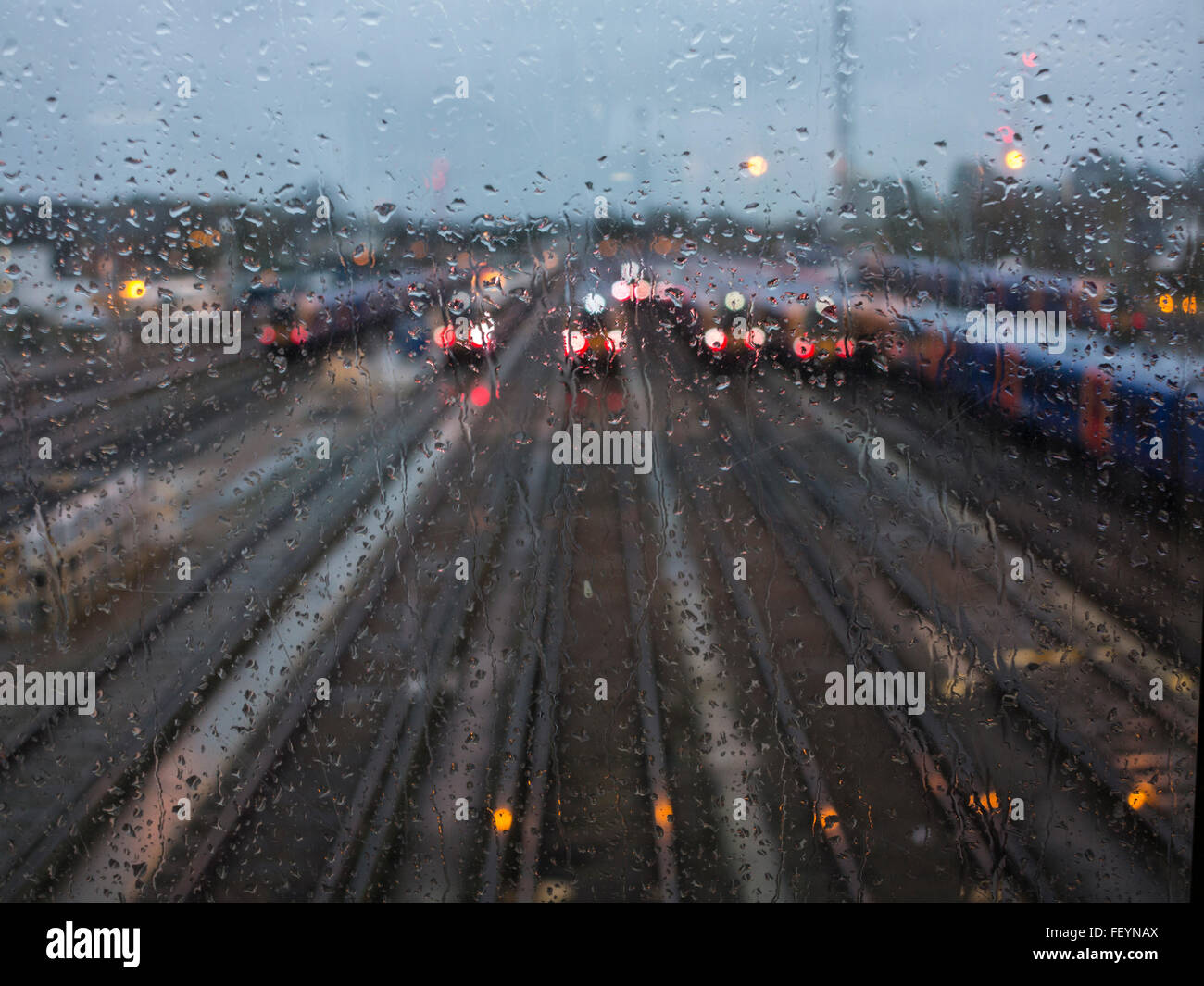 A dreary, rainy winter view of commuter trains through a wet window ...