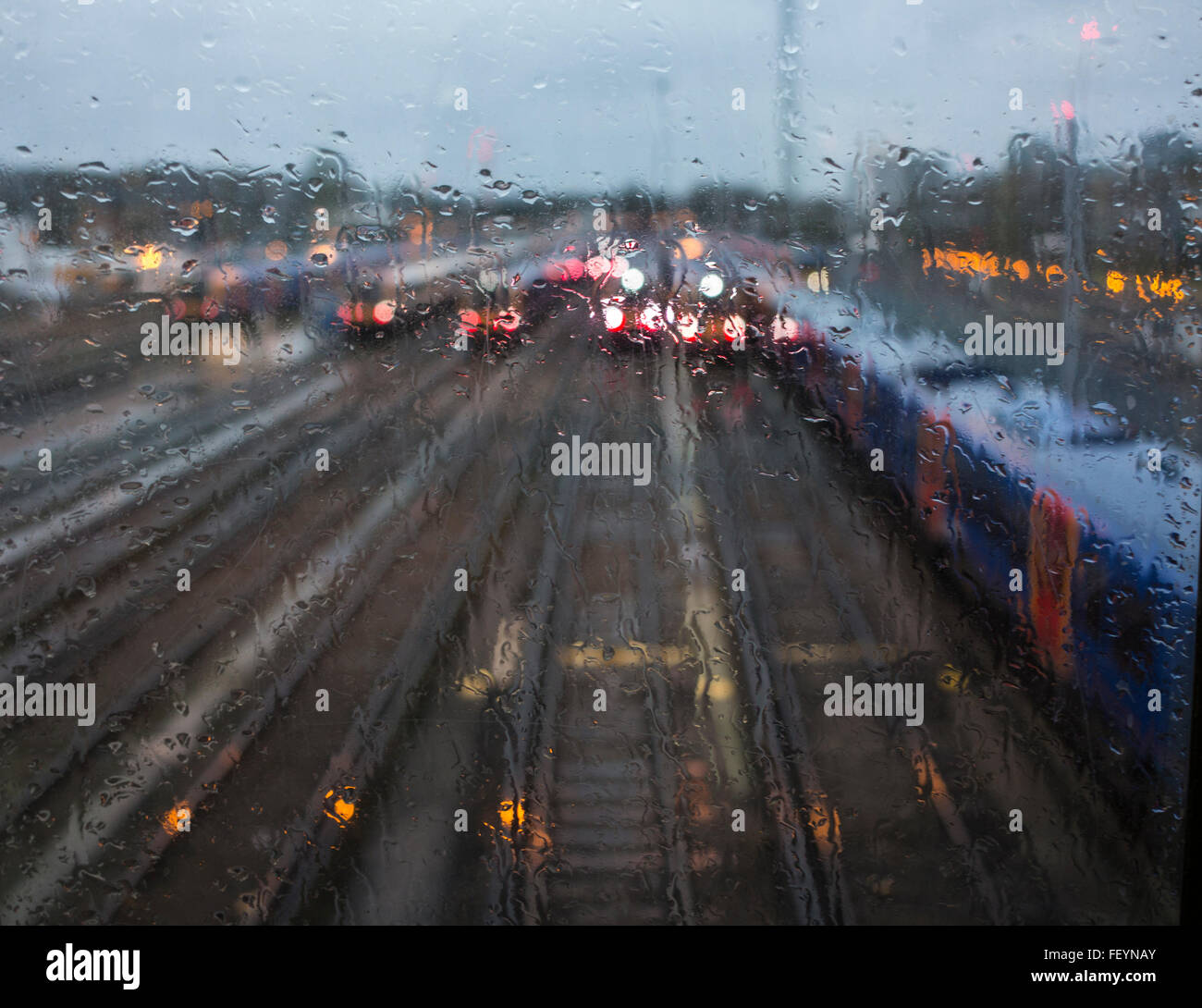 A dreary, rainy winter view of commuter trains through a wet window ...