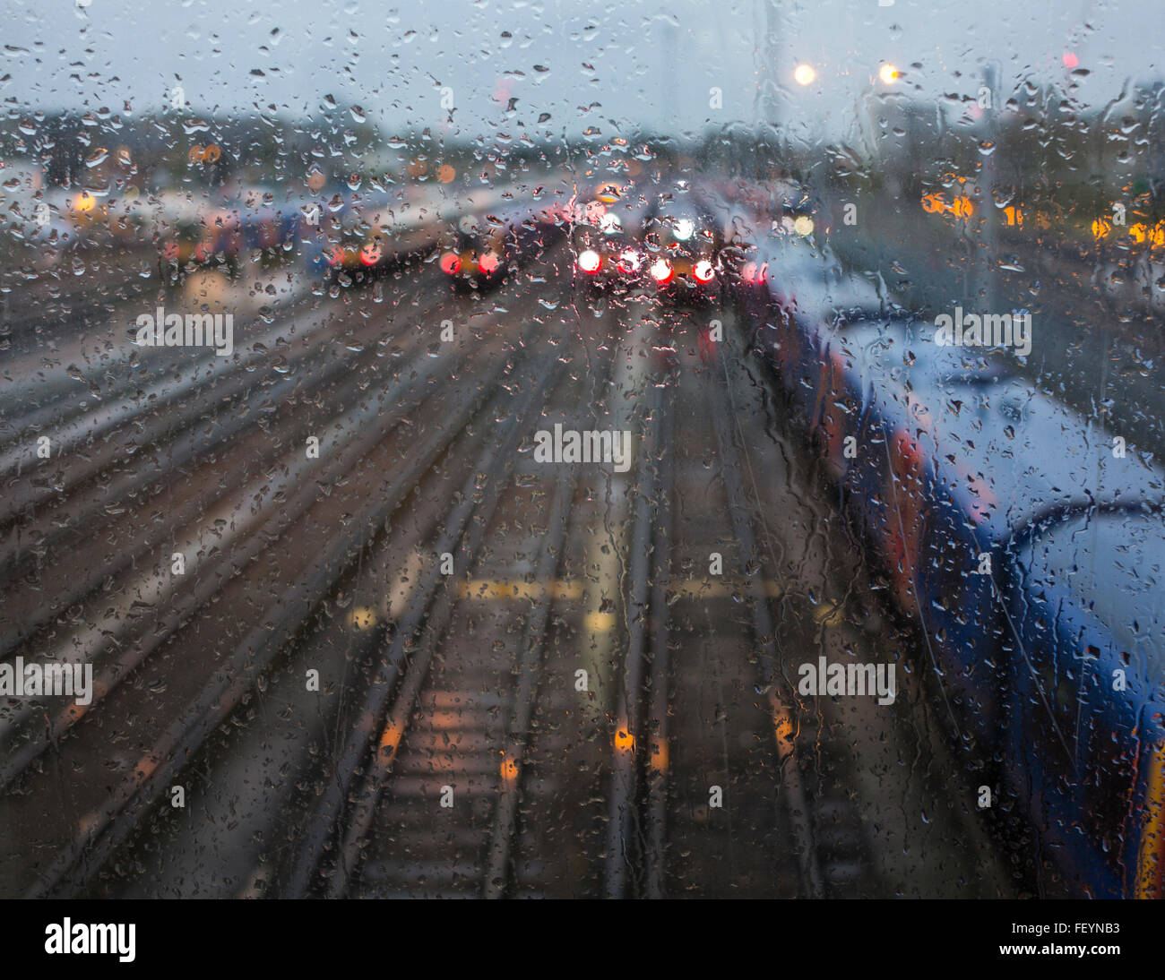 A dreary, rainy winter view of commuter trains through a wet window ...