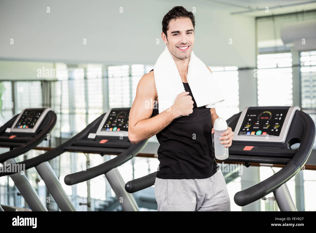 Smiling man on treadmill holding bottle of water Stock Photo - Alamy