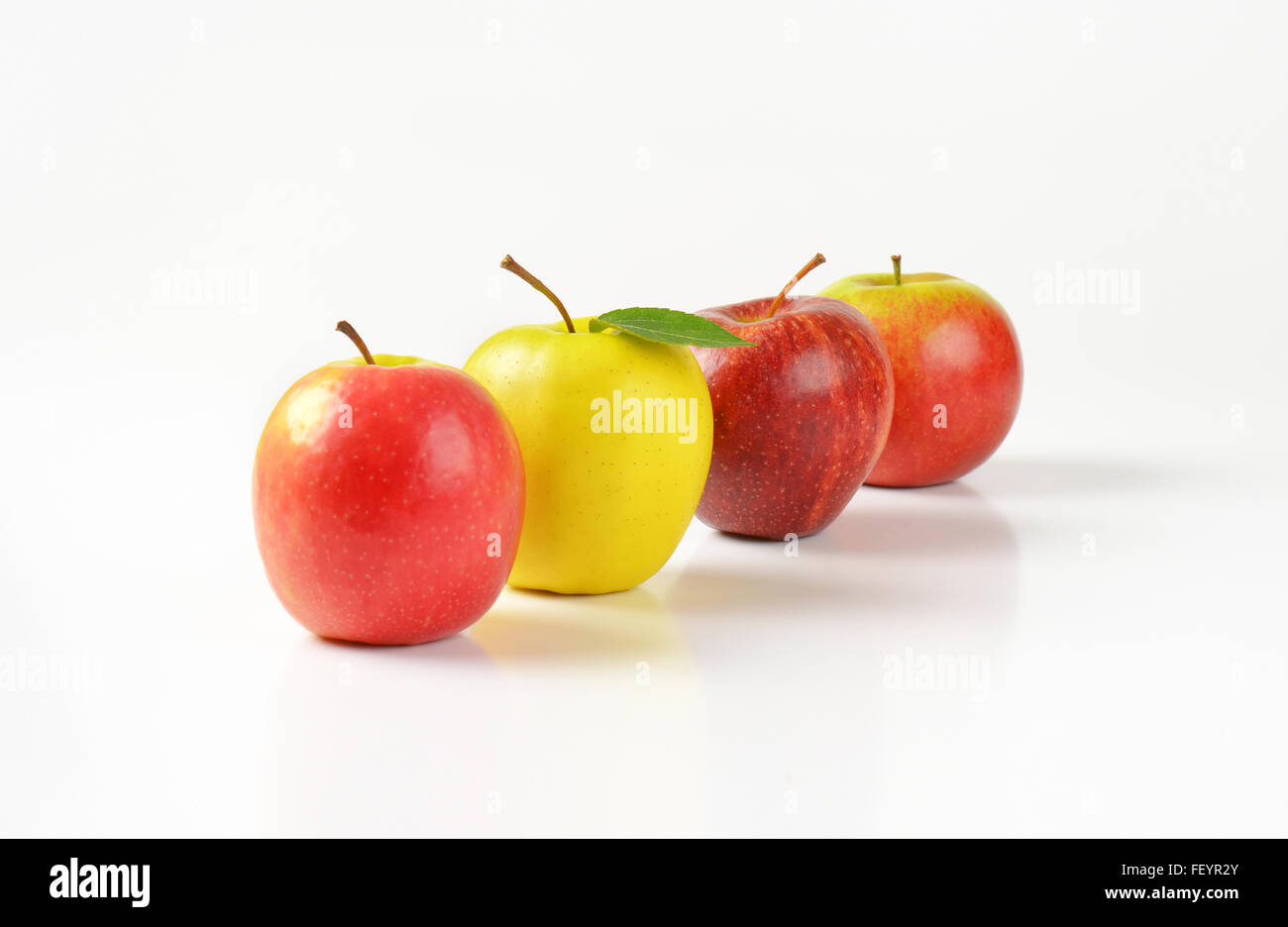 four ripe apples in a row on white background Stock Photo - Alamy
