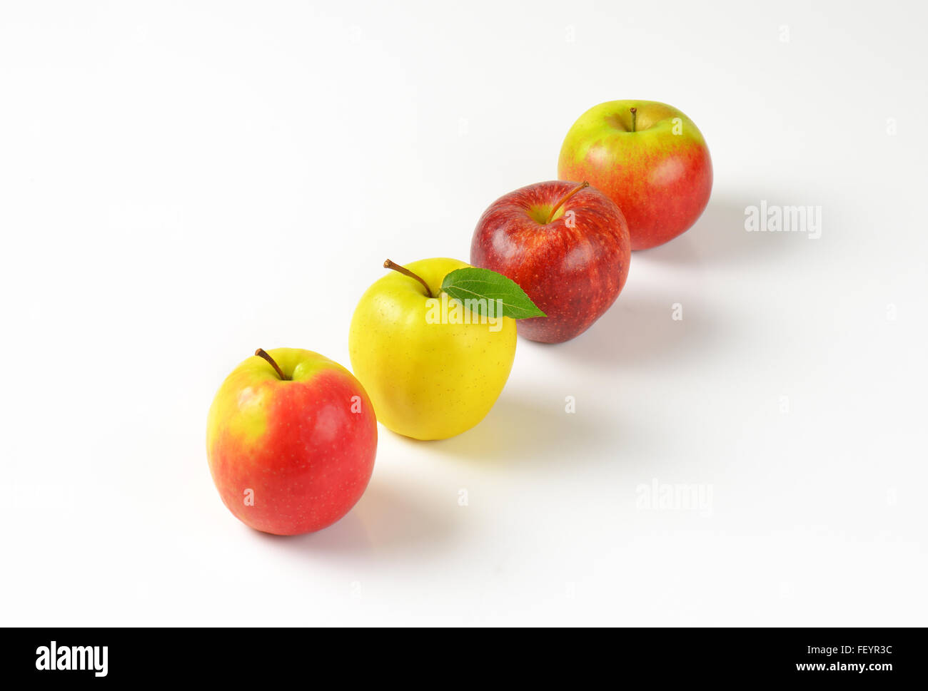four ripe apples in a row on white background Stock Photo - Alamy