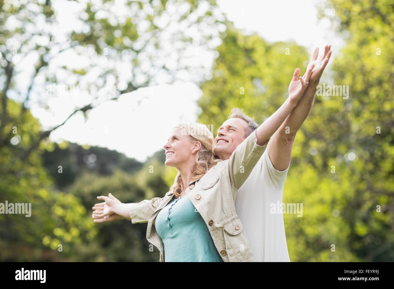Cute couple raising arms Stock Photo - Alamy