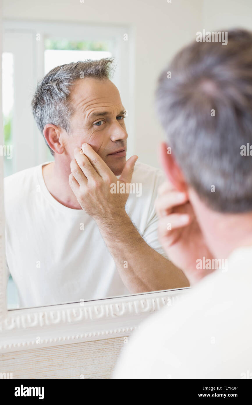 Handsome man looking at himself in the mirror Stock Photo - Alamy