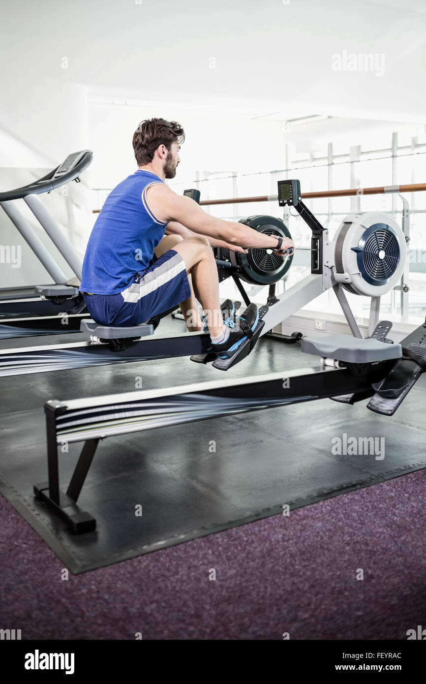 Handsome man doing exercise on drawing machine Stock Photo - Alamy