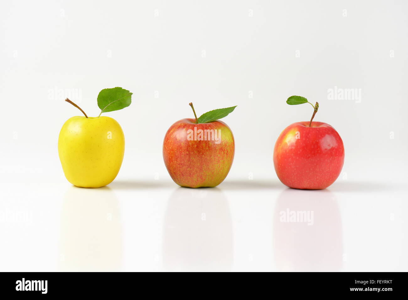 three ripe apples in a row on white background Stock Photo - Alamy