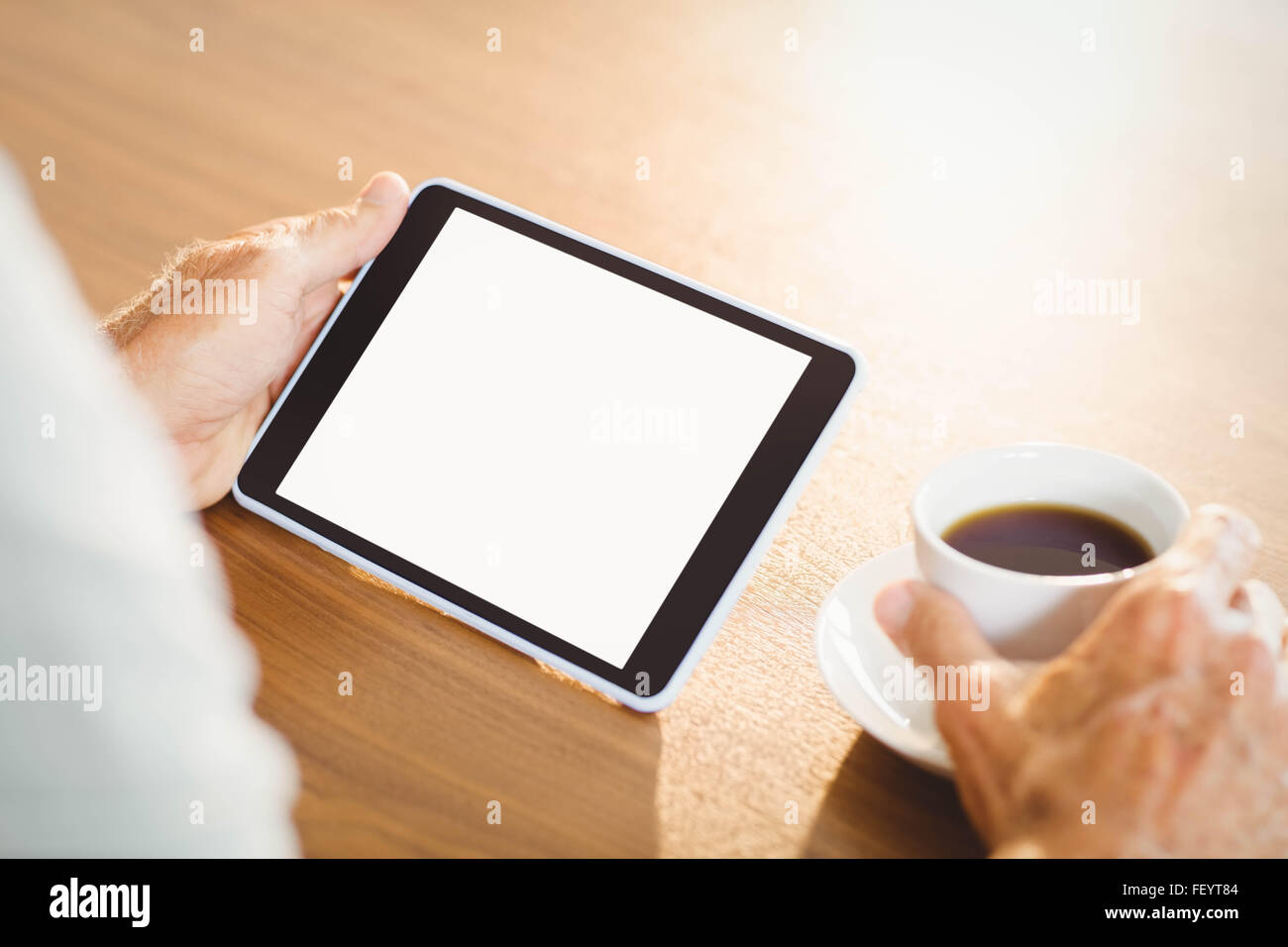 Elderly man using tablet and drinking coffee Stock Photo - Alamy