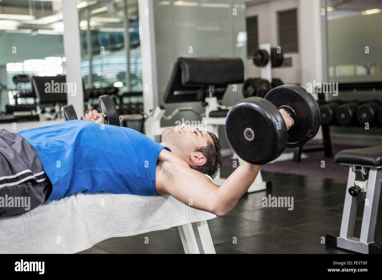 Handsome man lifting dumbbells on bench Stock Photo - Alamy
