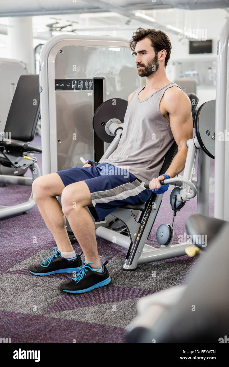 Focused man using weights machine for arms Stock Photo - Alamy