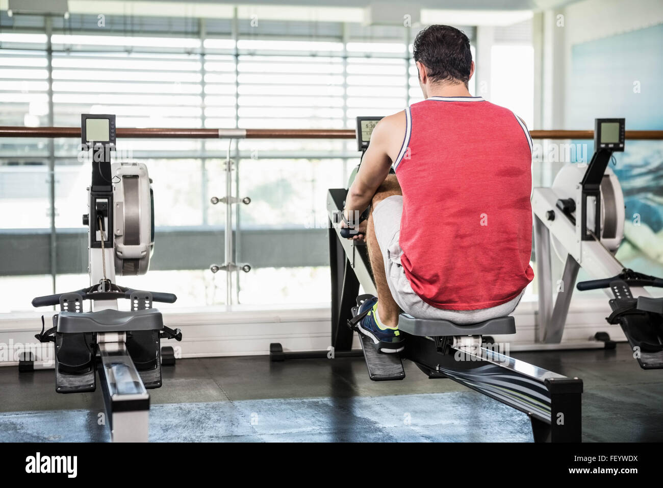 Muscular man on rowing machine Stock Photo - Alamy