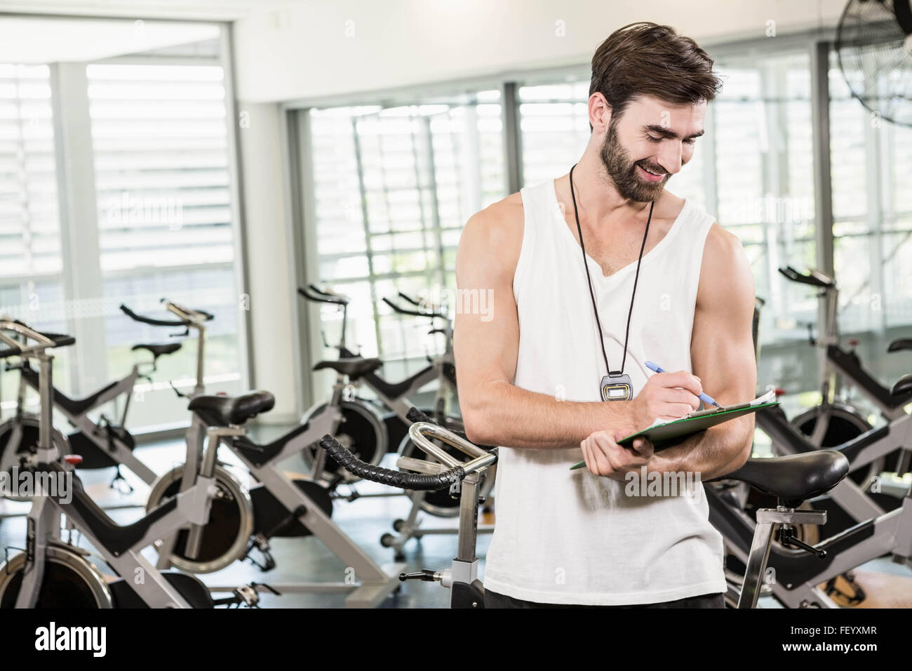 Smiling trainer writing on clipboard Stock Photo - Alamy
