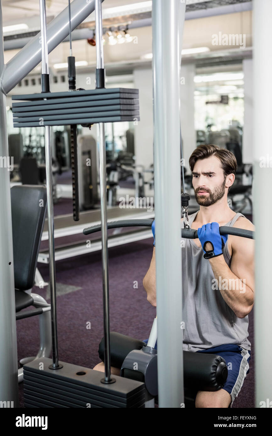 Focused man using weights machine for arms Stock Photo - Alamy