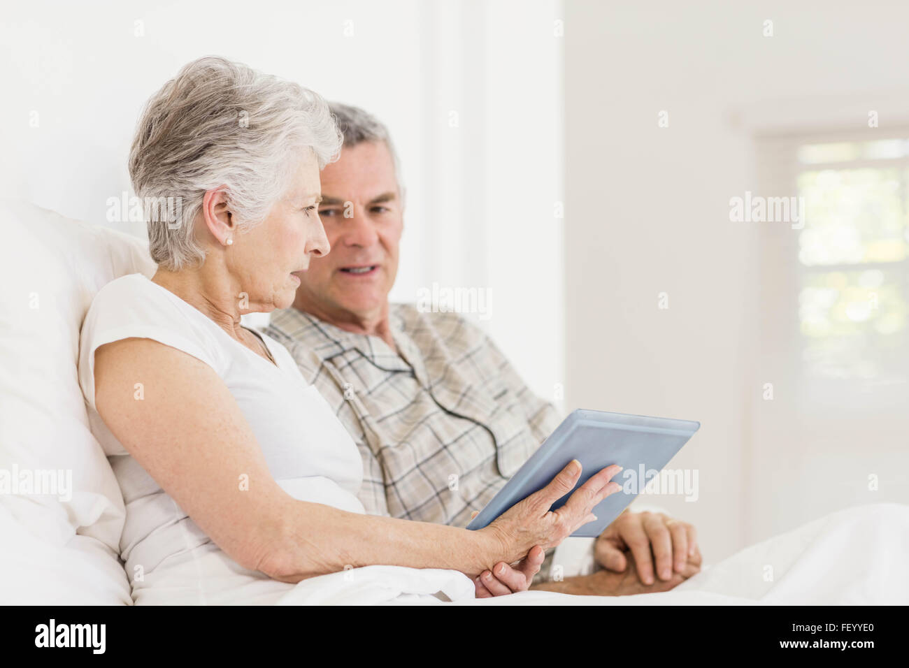 Senior couple using tablet on bed Stock Photo - Alamy