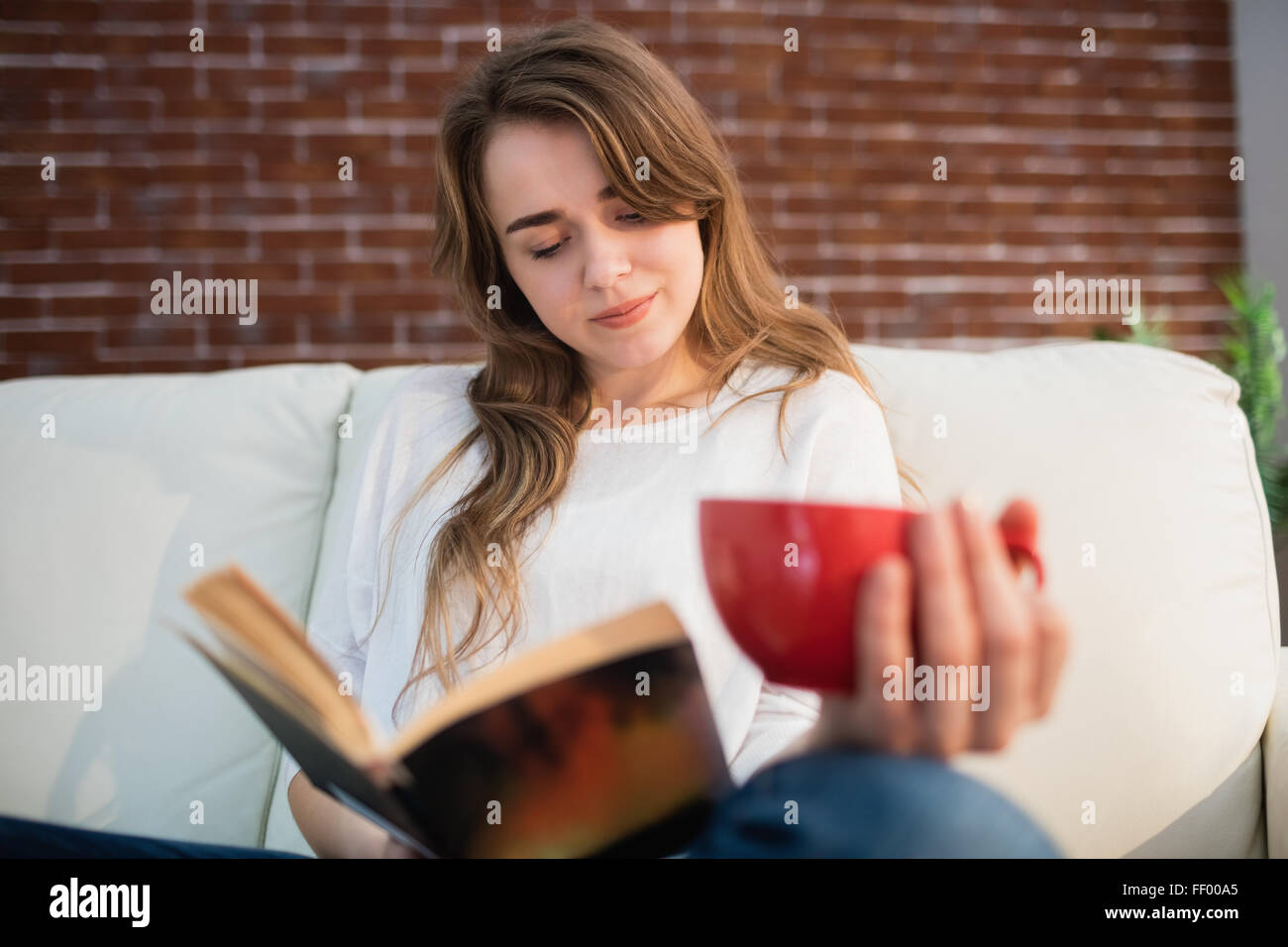 Focused woman reading a book while drinking Stock Photo - Alamy