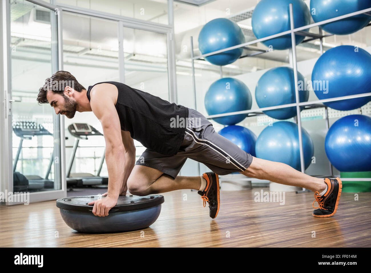 Serious man doing exercise with bosu ball Stock Photo - Alamy
