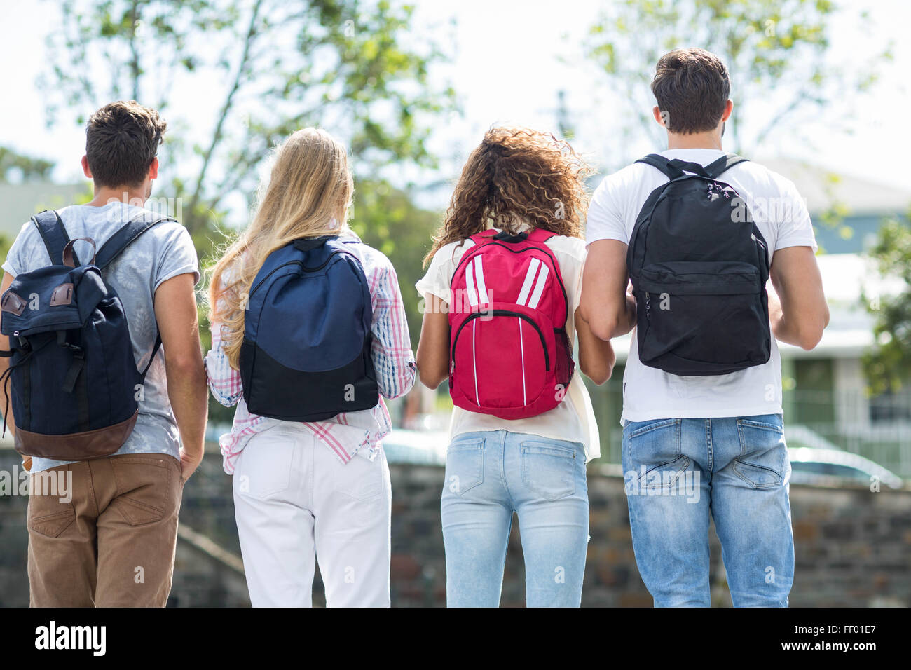 Rear view of hip friends with backpacks Stock Photo - Alamy