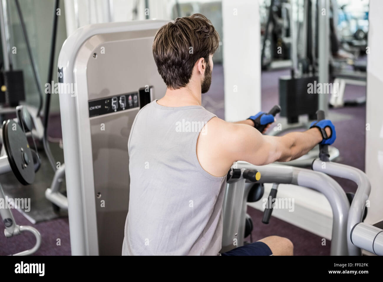 Focused man using weights machine for arms Stock Photo - Alamy