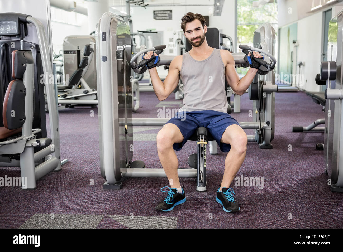 Focused man using weights machine for arms Stock Photo - Alamy