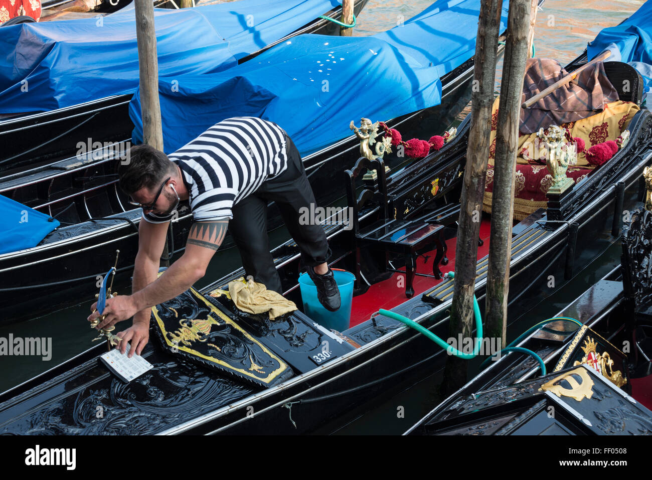 A gondoliere cleans his moored gondola at the start of another busy day ...