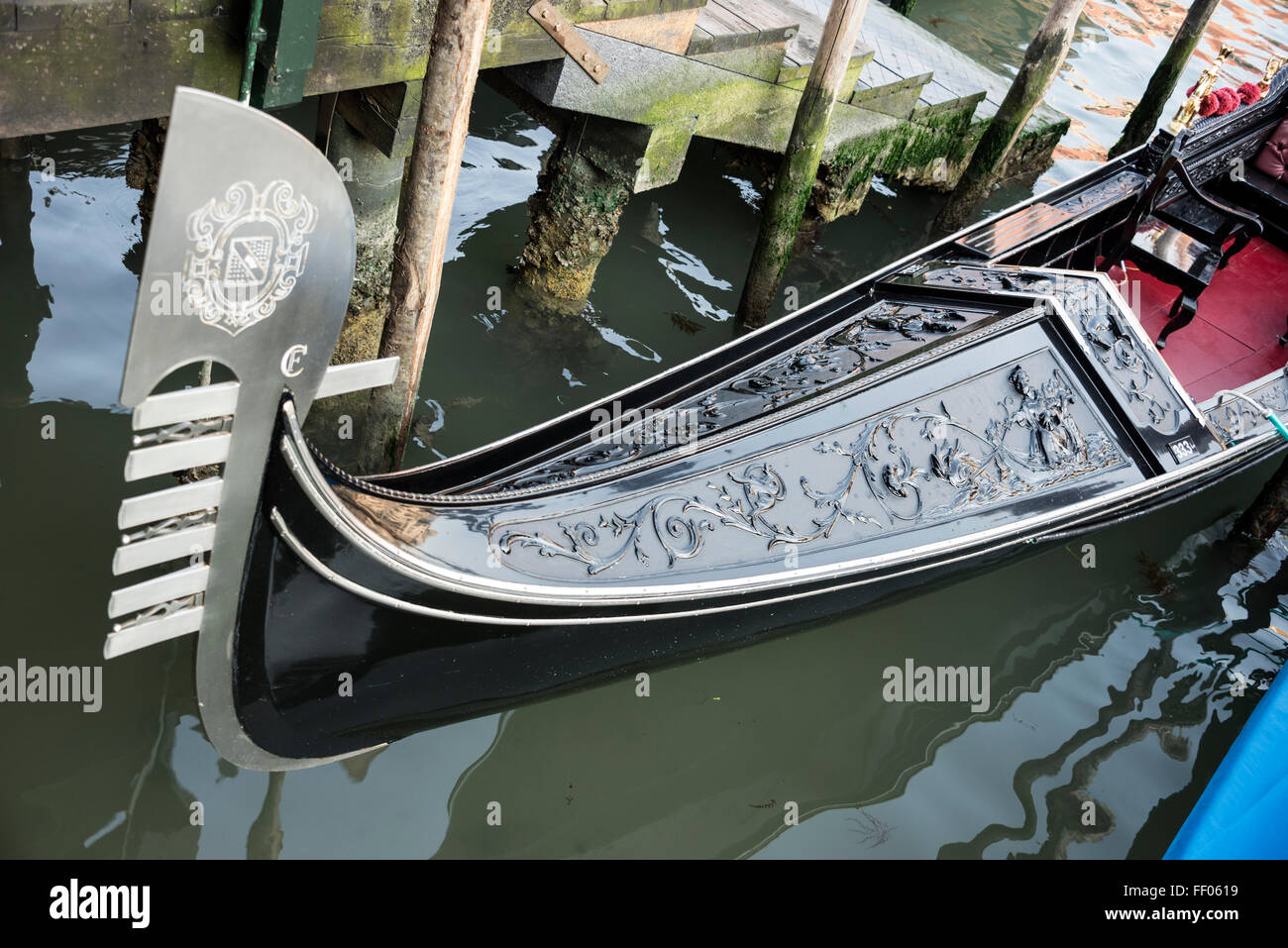 The traditional wooden carved deck of a moored black gondola on the ...