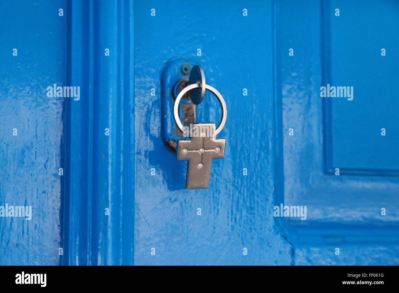 Blue door and the key in the lock with a tag in the shape of a cross ...