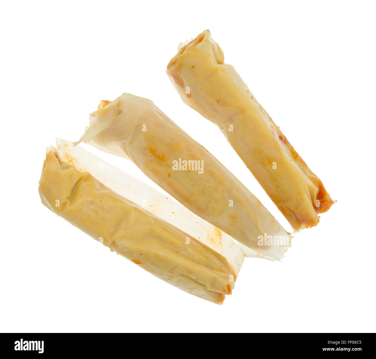 Three canned tamales wrapped in wax paper isolated on a white ...
