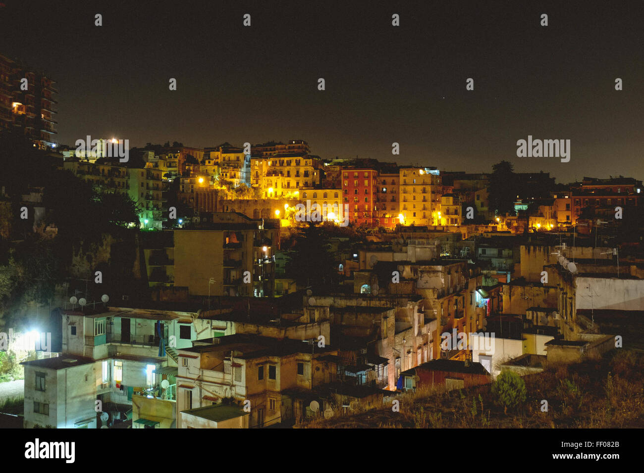 A hillside city illuminated at night, with residential apartments and ...