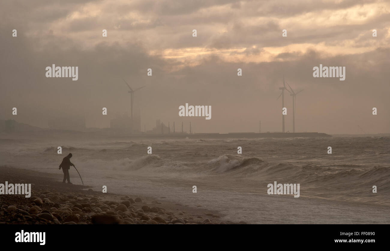 A dramatic beach scene showing storm clouds over the shoreline. The waves crash against the ...
