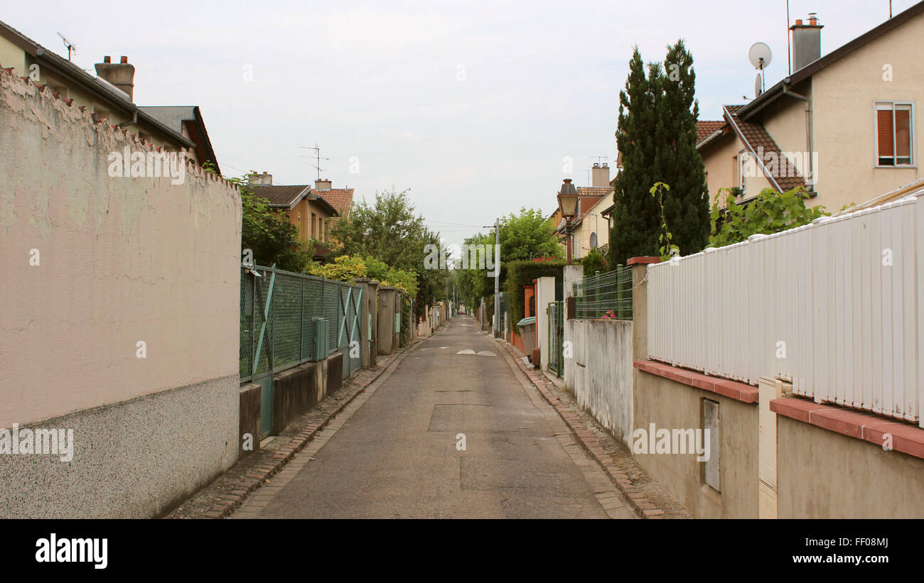 An alleyway in a residential neighborhood is shown, featuring a narrow ...