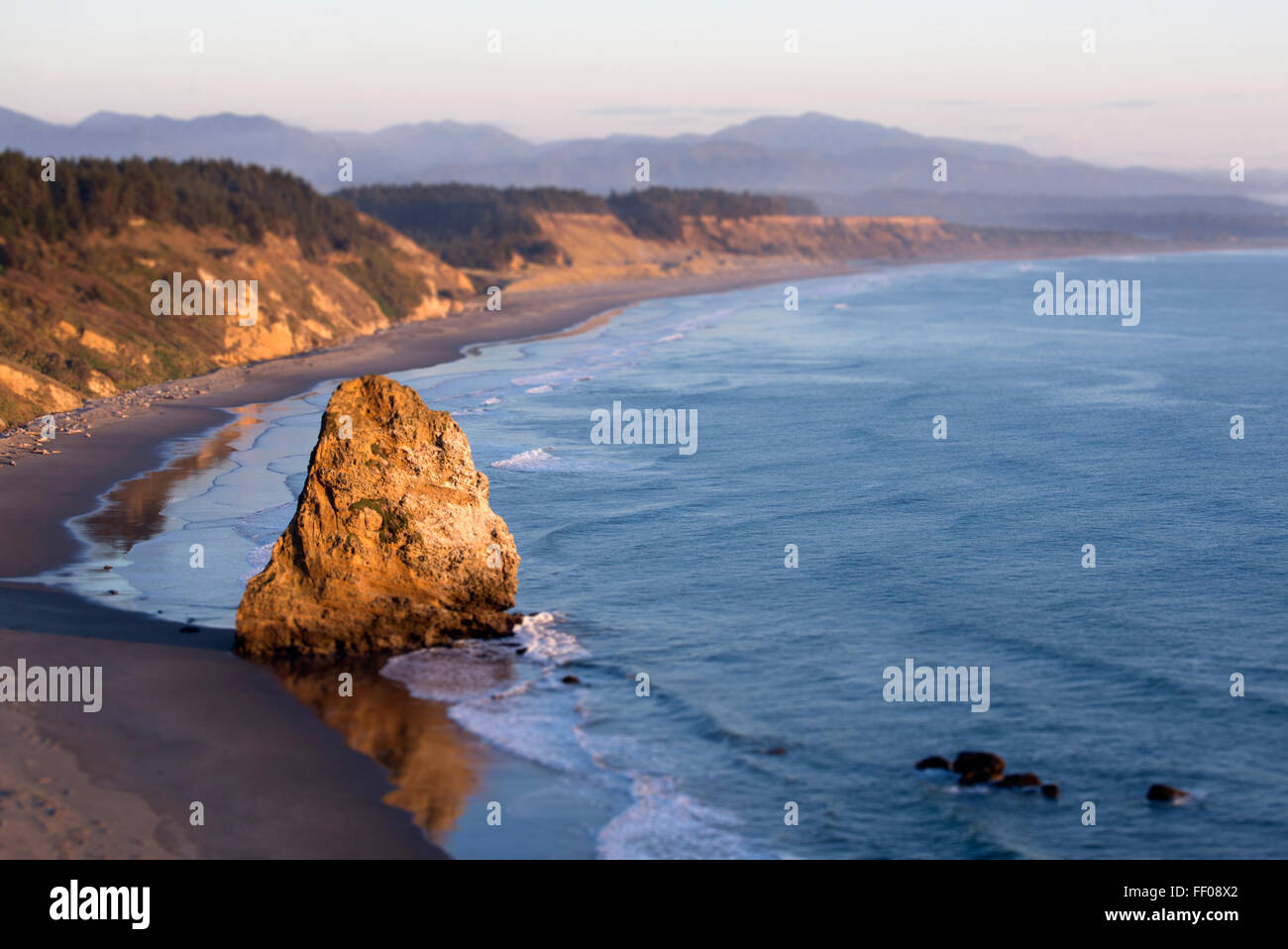 A small outcrop of rocks extends from the coastline, with the ocean ...