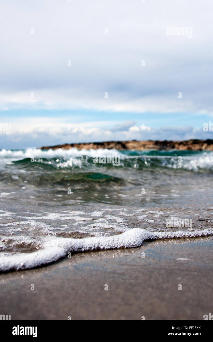 A close-up view of sea foam on the beach, where the waves meet the ...